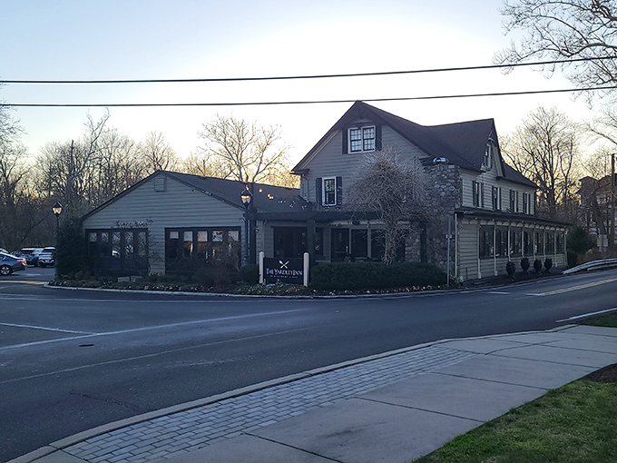 As dusk settles over Yardley, the inn's silhouette against the evening sky promises warmth and satisfaction within its historic walls.