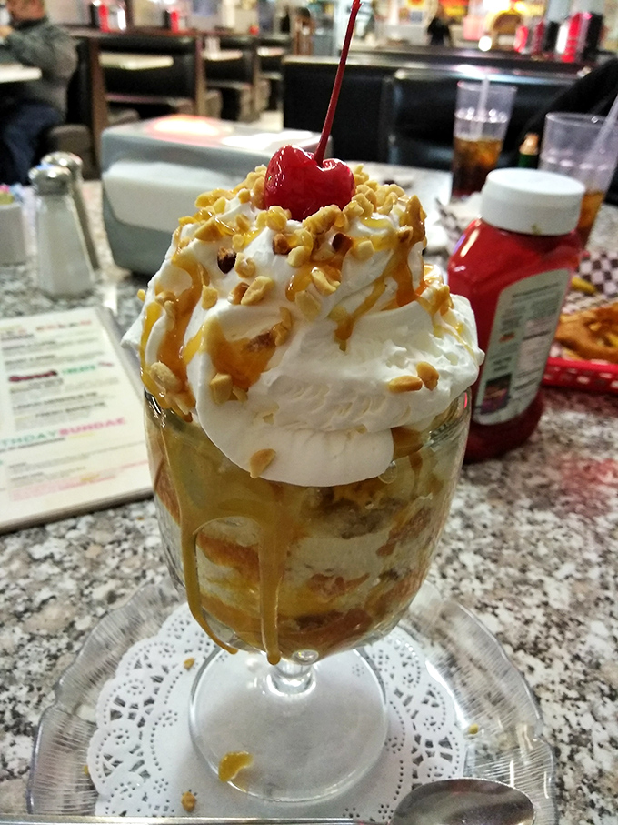 A sundae that defies gravity and good sense&mdash;whipped cream mountain, caramel rivers, and that cherry on top saying "you deserve this."