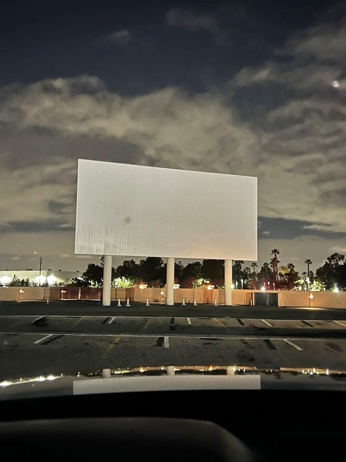 Under clouds illuminated by city lights, the massive blank screen waits patiently for its nightly transformation into a window to other worlds.