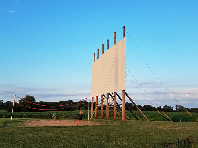 During daylight hours, the towering screen stands as a promise of evening entertainment, while kids squeeze in a game of catch before showtime.