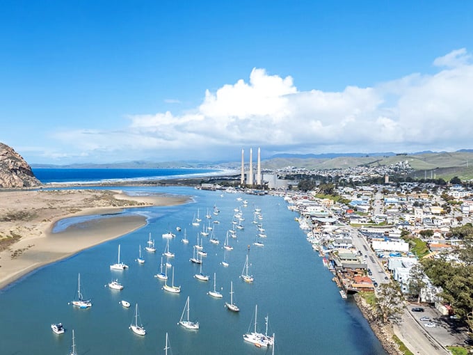 Morro Bay's iconic volcanic rock dominates the harbor where fishing boats, kayakers, and sea otters share protected waters beneath the ancient landmark.