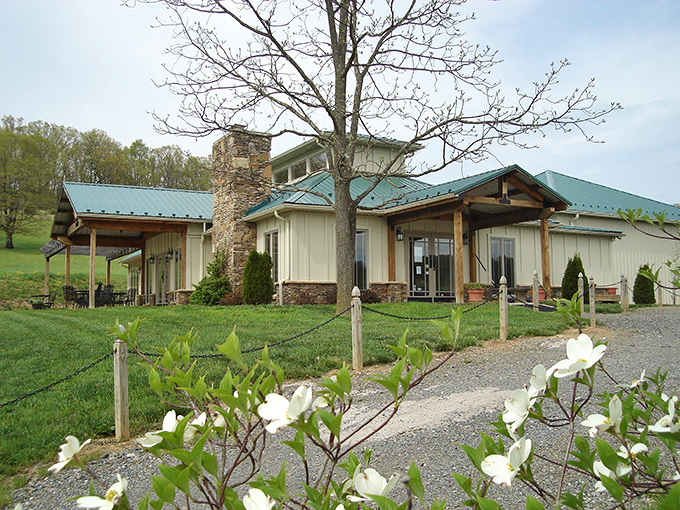 Blooming white dogwoods at West Wind Farm Vineyards & Winery greet you alongside a stone chimney and green-roofed tasting room.
