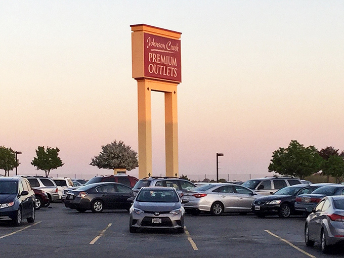 The iconic Johnson Creek Premium Outlets sign stands tall against the sunset sky, beckoning shoppers like a lighthouse of savings.