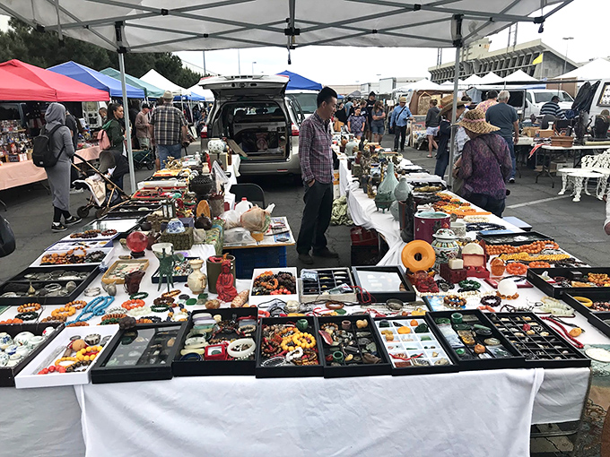 Treasure hunters gather around tables loaded with vintage finds, creating a collector's paradise under sunny California skies.