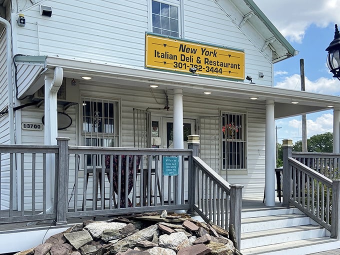 The charming white house exterior of New York Italian Deli promises old-school authenticity. That yellow sign is basically a beacon for sandwich lovers!