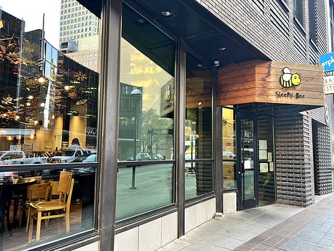 That cheerful bee logo practically buzzes with breakfast promise on Cincinnati's bustling downtown streets.