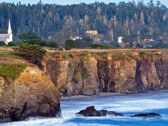 That church steeple reaches toward heaven while waves crash below in nature's own Sunday service.