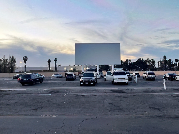 Twilight transforms this asphalt lot into a communal living room, where strangers become neighbors under the glow of Paramount's massive silver screen.