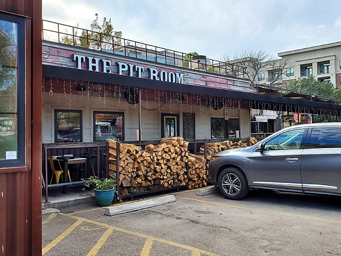 Stacked firewood outside The Pit Room isn't just decoration&mdash;it's a promise of smoky deliciousness waiting inside.