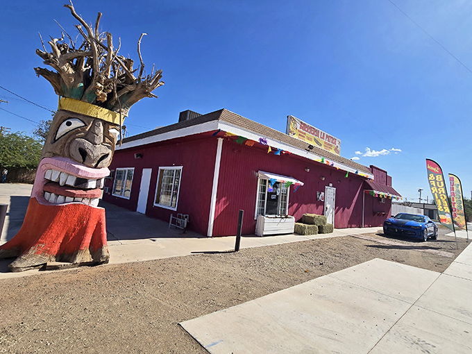 Local character on full display! This vibrant red restaurant with its whimsical tiki-inspired wooden sculpture proves desert towns don't lack personality.