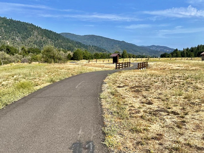 The path less traveled often leads to the best views. This paved trail invites both leisurely strollers and determined power-walkers to discover what lies beyond that wooden fence.