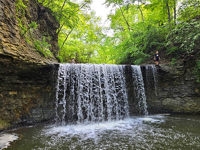 The waterfall doesn't roar so much as it whispers secrets, each droplet part of a centuries-old conversation between water and stone.