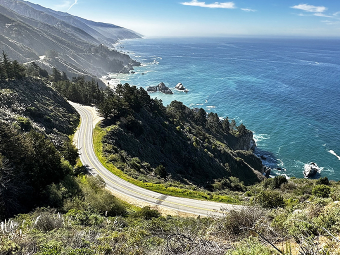 Highway 1 hugging the coastline like it's afraid of heights but can't resist the view. California's ultimate road trip moment.