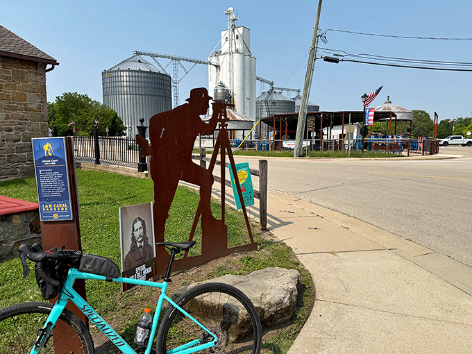 That metal silhouette isn't just art&mdash;it's a nod to the surveyors who first mapped this land, standing sentinel as grain silos rise in the background.