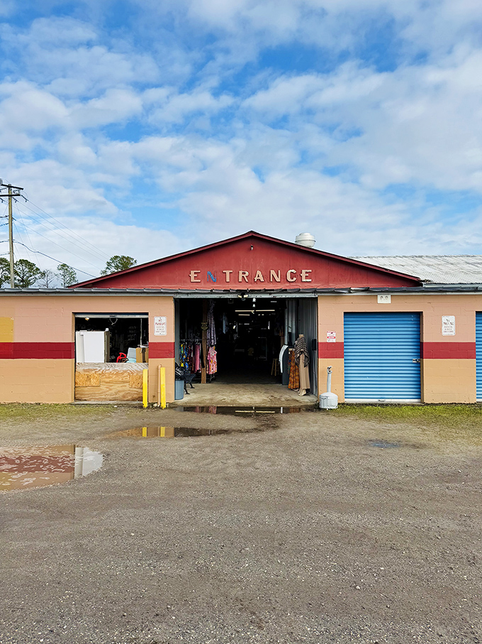 The iconic red entrance building stands sentinel under Florida's vast sky, promising adventures in bargain-hunting just beyond its humble facade.