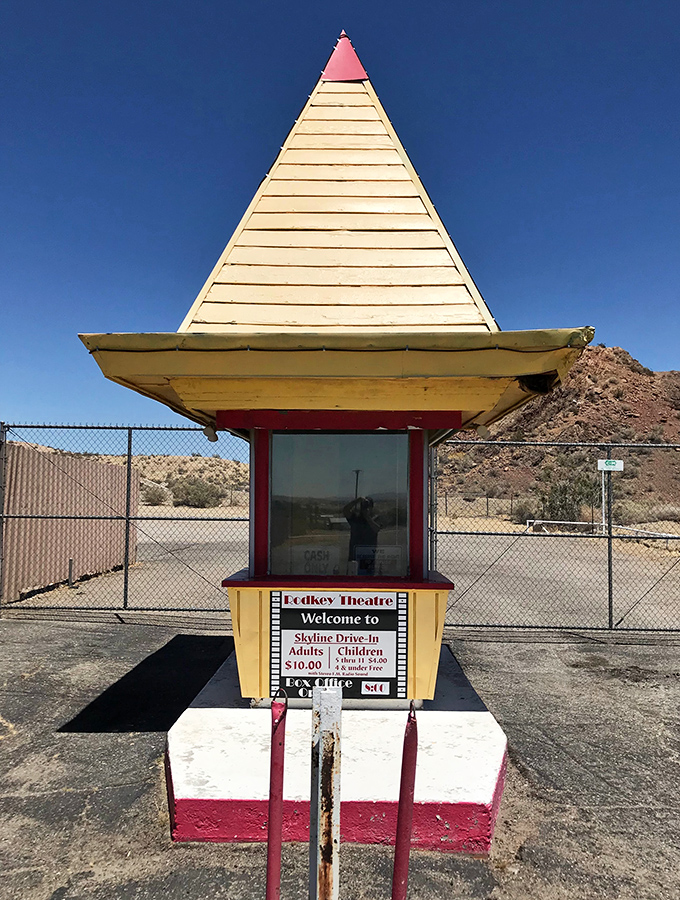 The iconic yellow pyramid ticket booth stands as a cheerful sentinel, welcoming movie lovers to a slice of Americana.