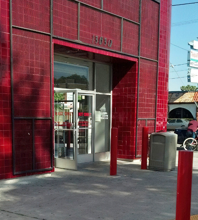 The entrance beckons with all the subtlety of a game show host, those red pillars standing guard like sentinels protecting a warehouse of wonders.