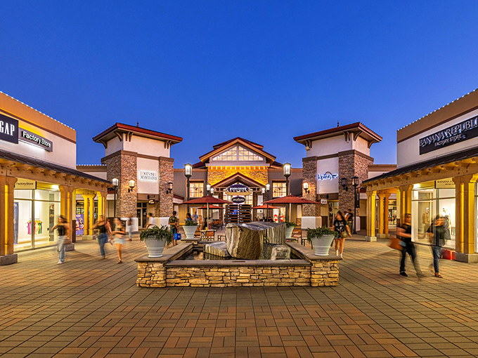 As dusk settles, the central plaza transforms into a glowing retail oasis. That fountain isn't for wishes&mdash;it's for resting your shopping bags while plotting your next store conquest.