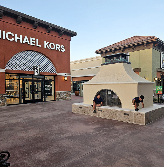 The Michael Kors storefront stands proudly in terra cotta splendor, while children discover the simple joy of a decorative fireplace structure&mdash;shopping and entertainment in one stop!