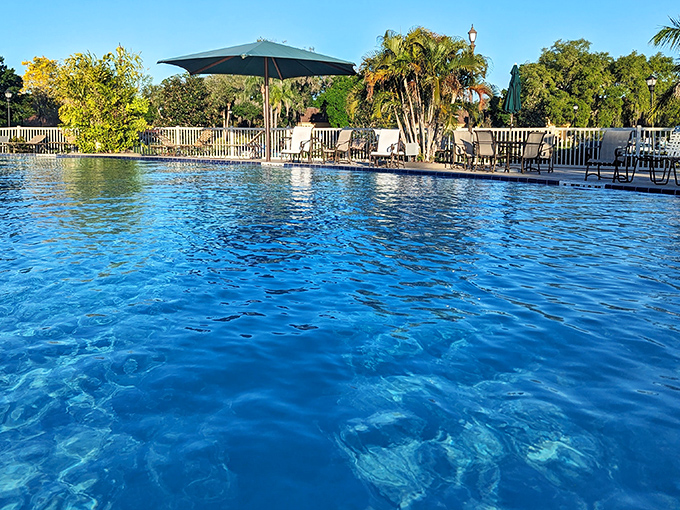 The community pool sparkles like a sapphire under the Florida sun, surrounded by palm trees and comfortable seating for post-swim socializing.