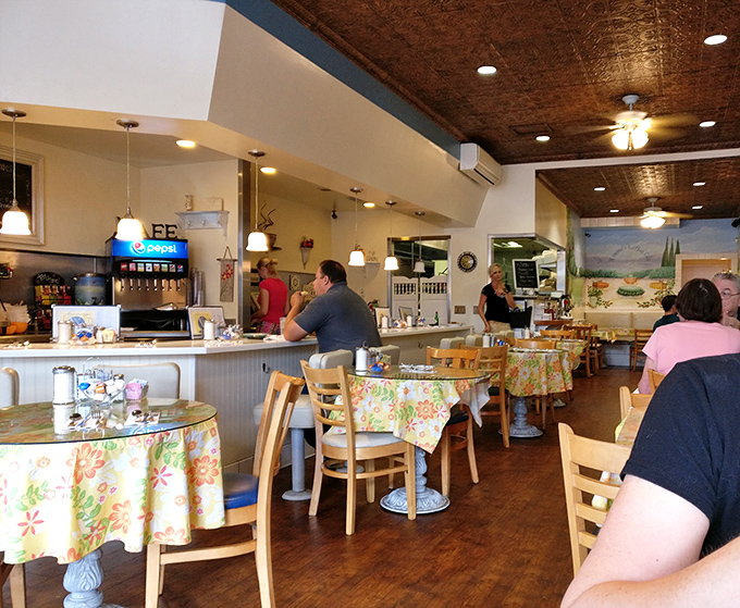 Floral tablecloths, warm wood tones, and that distinctive copper ceiling create the perfect backdrop for morning conversations and coffee refills.
