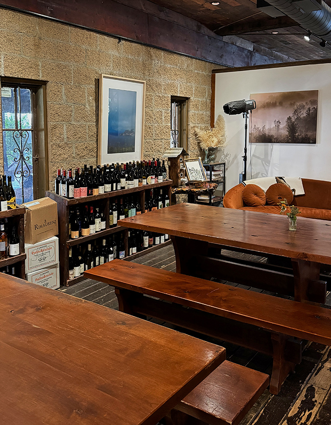 Communal tables and wine bottles line the rustic interior, creating an atmosphere where strangers become friends over shared plates and stories.