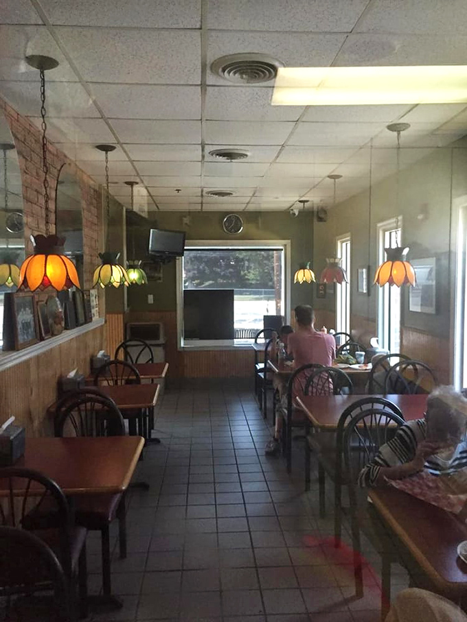 Tiffany-style pendant lamps cast a warm glow over simple wooden tables, creating that classic pizzeria ambiance where memories are made one slice at a time.