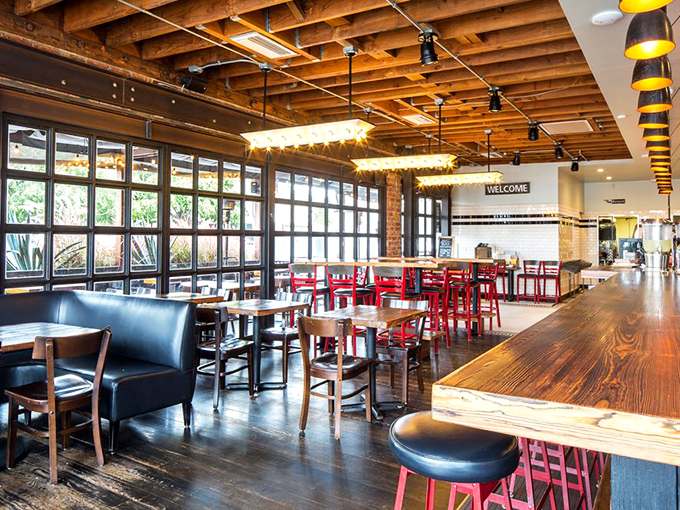 Industrial-chic meets barbecue comfort in this thoughtfully designed space where exposed wooden beams and red chairs create the perfect backdrop for meat-induced happiness.