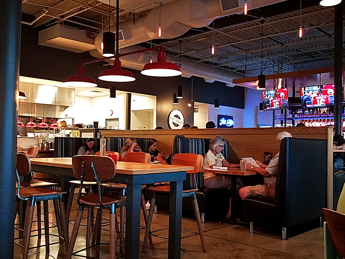 Industrial meets inviting with red pendant lights casting a warm glow over comfortable booths. The kind of place where calories don't count and conversations flow freely.