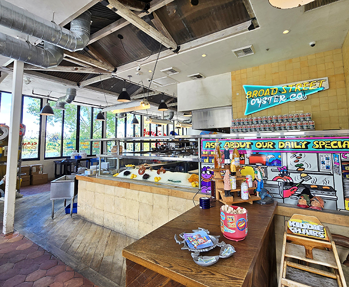 Industrial chic meets beach shack vibes inside, where exposed ducts hover above colorful walls adorned with whimsical sea-inspired art that telegraphs the kitchen's playful approach to serious seafood.