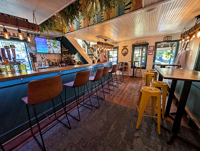 The interior combines rustic wooden floors with pops of yellow metal stools, creating a space that feels both beachy and intimate&mdash;like your coolest friend's vacation home.