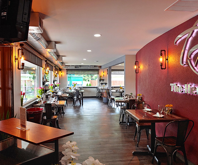 The warm burgundy accent wall and industrial-chic seating create that perfect sweet spot between "nice enough for date night" and "comfortable enough for breakfast in sweatpants."