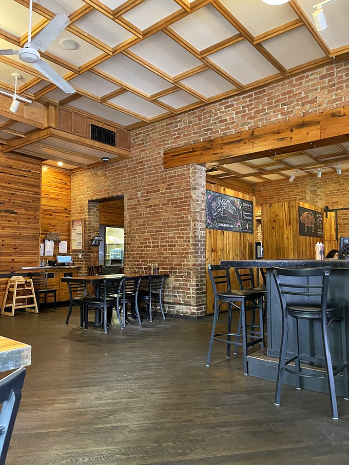 Exposed brick meets warm wood paneling under a coffered ceiling—proof that serious barbecue deserves serious architecture.