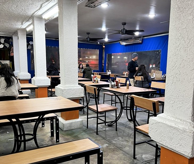 Simple wooden tables and white columns create a no-nonsense dining space where the food, not the decor, rightfully takes center stage.