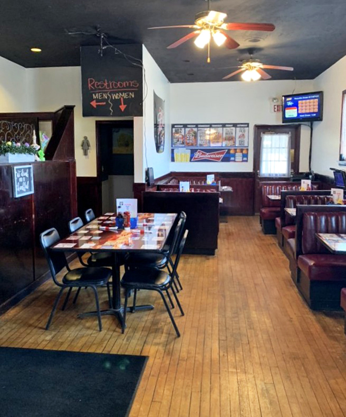 Inside, wooden floors and cozy booths tell stories of countless meals shared, while ceiling fans lazily spin above conversations waiting to happen.