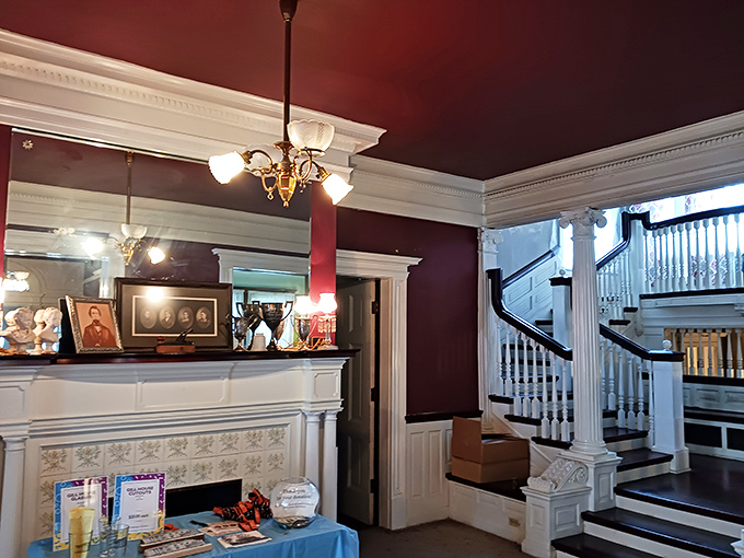 Rich burgundy walls and gleaming white woodwork create a dramatic backdrop for the grand staircase, where countless footsteps have polished the wood to a satin finish.