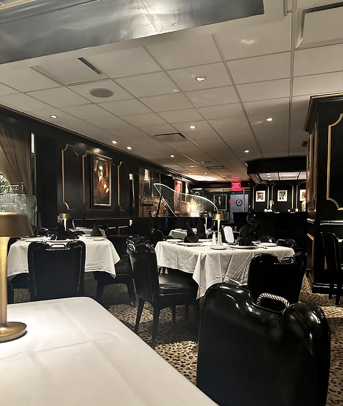 Step into a time machine disguised as a dining room. The leopard print carpet, black leather chairs, and crisp white tablecloths transport you to an era when dinner was an event.