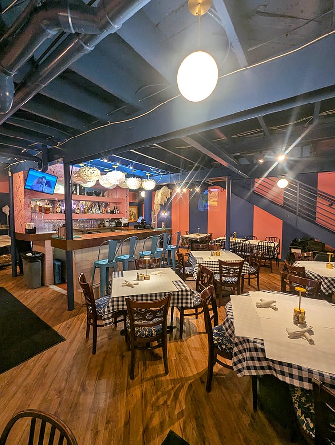 Wooden floors, checkered tablecloths, and orange accent walls create that perfect "come as you are, leave fuller than you planned" vibe.