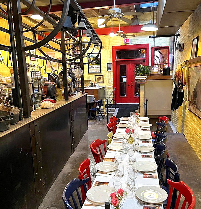 Vibrant yellow walls and colorful chairs create a warm, inviting atmosphere where communal dining turns strangers into friends over shared pasta.