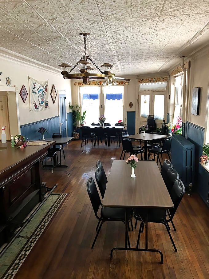 Sunlight streams through blue-trimmed windows onto wooden floors that have supported generations of comfort food enthusiasts. The tin ceiling whispers stories of meals past.