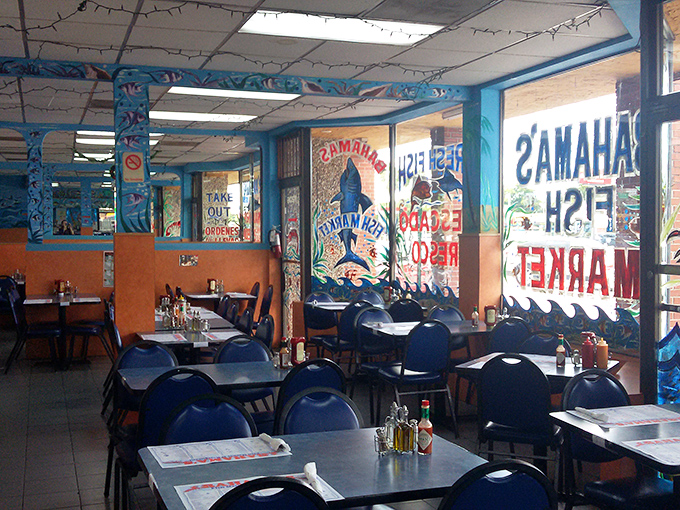 Vibrant maritime murals transform this humble dining room into an underwater fantasy. Blue chairs and orange walls create the perfect backdrop for seafood adventures.
