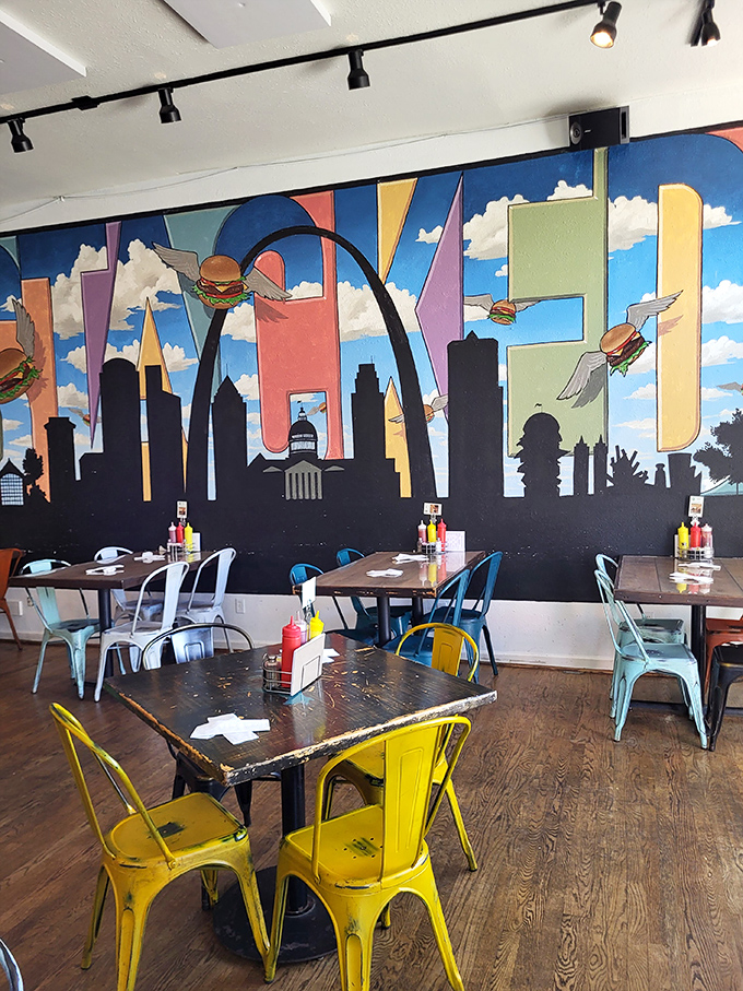 Colorful metal chairs pop against the whimsical St. Louis skyline mural where flying burgers soar past the Gateway Arch&mdash;dinner and a show!