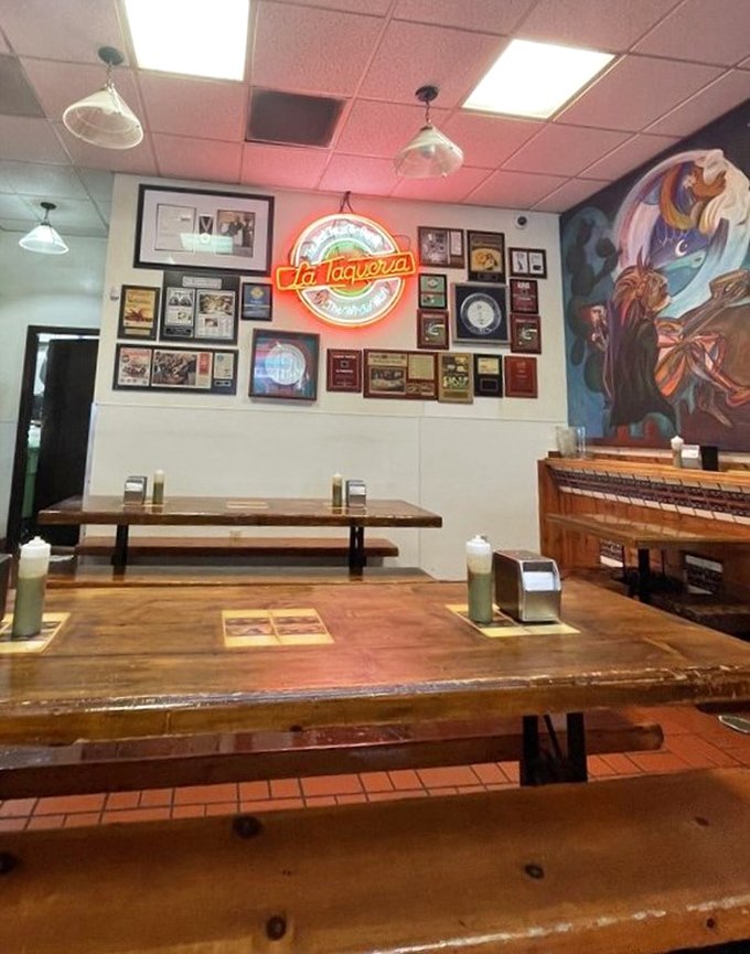 Wall of fame meets neon glow. Decades of accolades line the walls while wooden tables await the next generation of burrito believers.