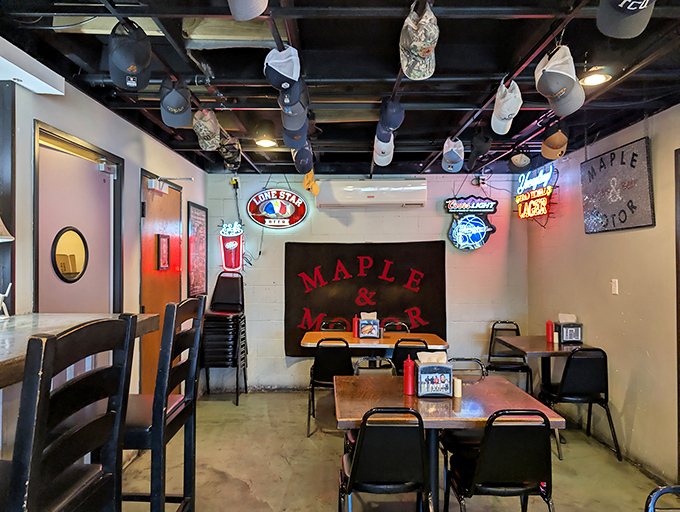 Baseball caps dangle from the ceiling like tasty memories, while neon signs cast a warm glow over simple tables where food matters more than frills.