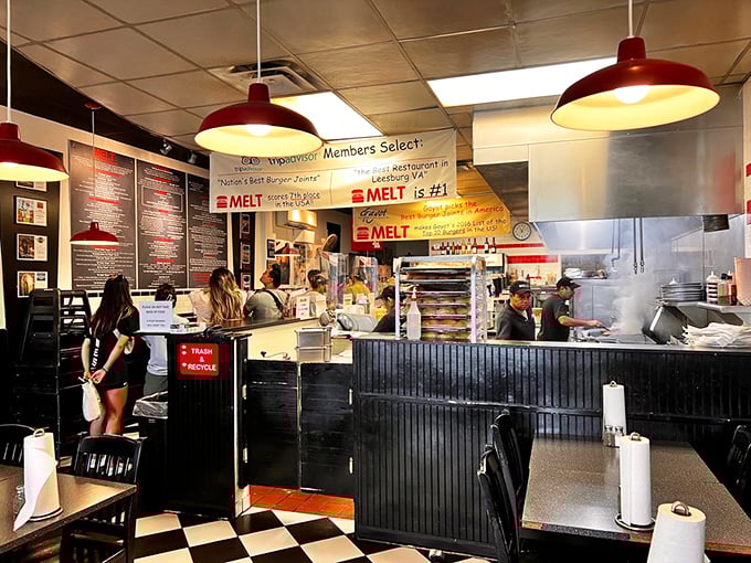 The open kitchen design lets you witness the burger alchemy in progress. Red pendant lights cast a warm glow over the checkered floor &ndash; burger joint perfection.