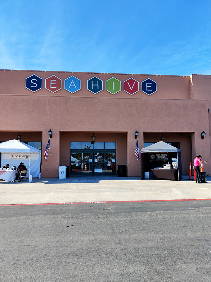 A second view of Sea Hive's inviting fa&ccedil;ade, where American flags flutter beside pop-up vendor tents, hinting at the community of creators inside.