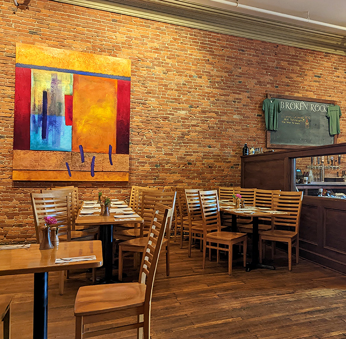 Exposed brick walls meet vibrant local artwork in this dining room that feels like the living room of that friend who actually has their life together.