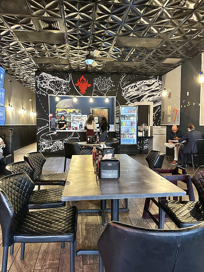 The sleek interior combines modern design with comfort, featuring eye-catching metallic ceiling tiles and artistic burger murals.