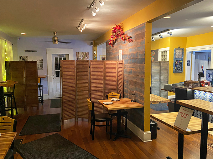 Wooden dividers and sunny yellow walls create intimate dining spaces that feel like you've stumbled into someone's cherished family kitchen.