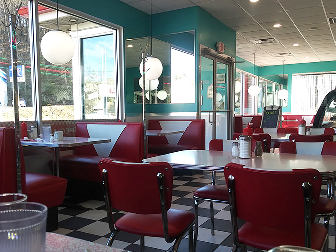 Step into a time machine of teal and cherry red, where the checkerboard floor sets the stage for culinary nostalgia that never goes out of style.